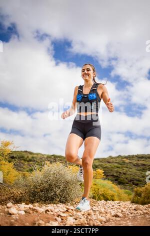 Female trail runner wearing black sportswear and a hydration vest ...