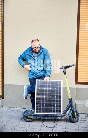 Male person holds photovoltaic solar panel, for charging electric ...