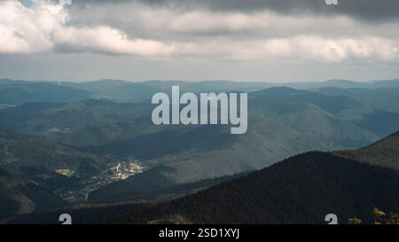 A sweeping view of rolling mountain ranges under a cloud-filled sky ...