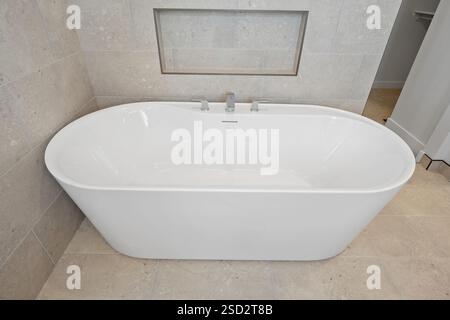 White bathtub placed in light bathroom with ceramic sinks and mirror ...