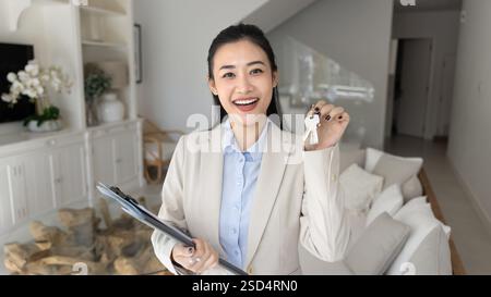 Happy young Asian woman showing heart gesture on blue background ...