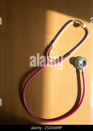 On a light wooden table there is a stethoscope, a pen and a sheet of ...