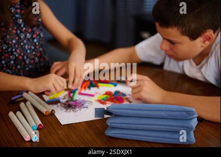 Two kids collaborating on an art project using crayons and markers ...