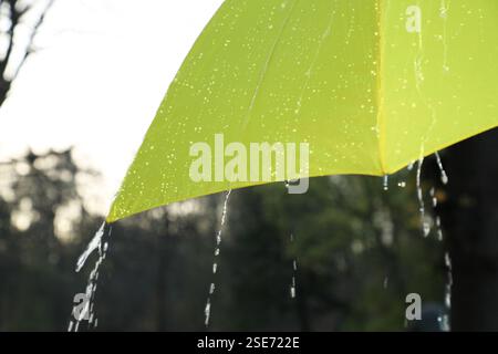 Open yellow umbrella under pouring rain outdoors, closeup. Space for ...