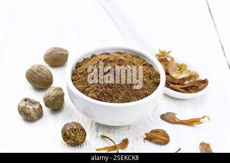 Dried nutmeg arillus and ground nutmeg in two spoons, whole nuts on ...