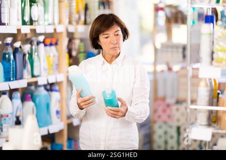 Female buyer chooses shampoo or shower gel in household goods ...