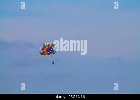 A colorful parachute with two people soaring high in the sky against a ...