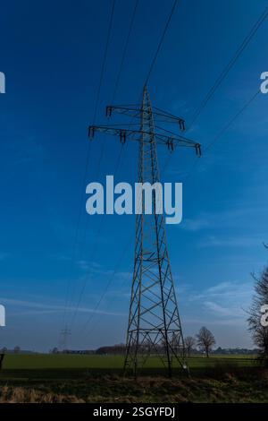 Strommast mit Hochspannungsleitungen vor blauem Himmel, zentrale Sicht ...