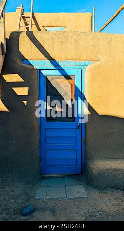 Rustic Adobe Home with Vibrant Blue Door and Shadows Stock Photo - Alamy