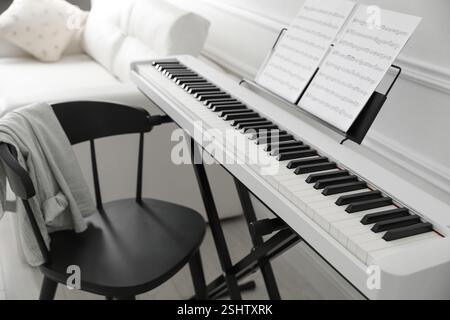 Synthesizer with music sheets and chair at home, closeup Stock Photo ...