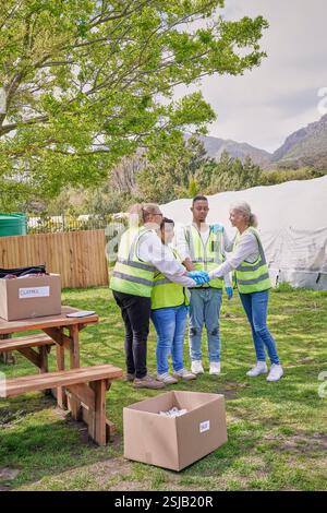 Group of volunteers standing and holding hands over donation boxes ...