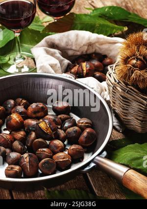 Roast chestnuts in a pan on a wooden table. White background. Top view ...