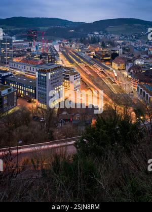 An aerial shot of a train station in Switzerland surrounded by a forest ...
