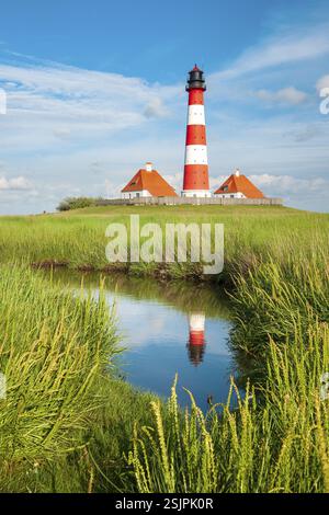 A lighthouse in the middle of a sea under a pink and blue clouded sky ...