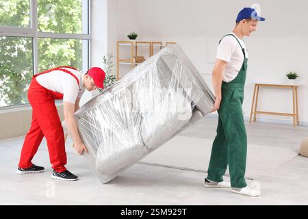 Loaders carrying sofa in stylish room Stock Photo - Alamy