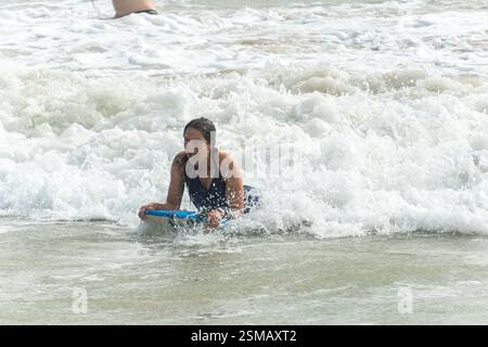 A Caucasian man with a boogie board swimming in sea waves at Bethany ...