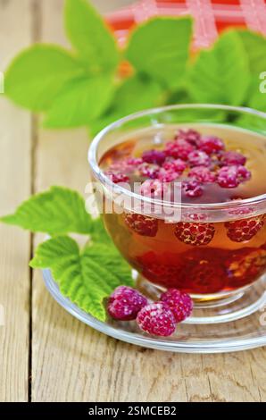 Tea with raspberries in a glass cup, green leaf raspberry isolated on a ...
