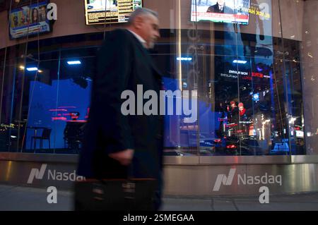 People walk past a Nasdaq sign below a lighting installation of the ...