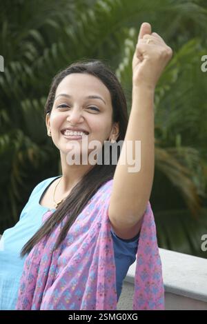 young lady lifting one hand with fist and expressing winning position ...
