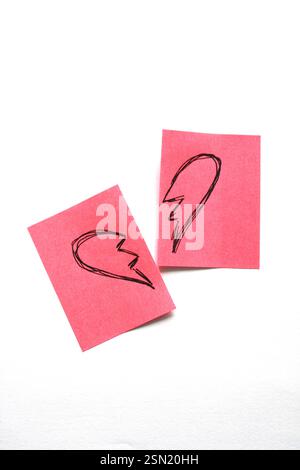 Two pieces of pink sticky note torn apart with two parts of a broken ...
