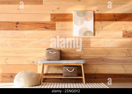 Baskets on bench and pouf near wooden wall in room Stock Photo - Alamy