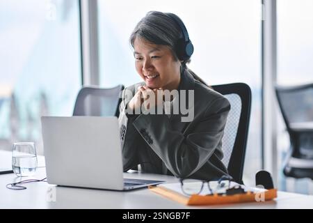 Happy mature woman in headphones scrolling music playlist on online ...