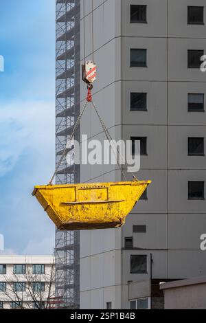 Yellow old skip bin hanging on chains Stock Photo - Alamy