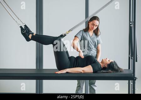 Legs is on the stretching cable. Woman is in health center getting help ...