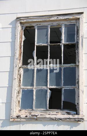 Old grid windows with broken glass on exterior wall of an old abandoned ...