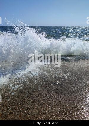 Stormy sea waves crash against a rocky shore. Waves crashing over rocks ...