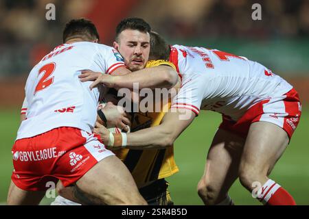 Tom Davies of Hull KR is tackled by Ethan Havard of Wigan Warriors and ...