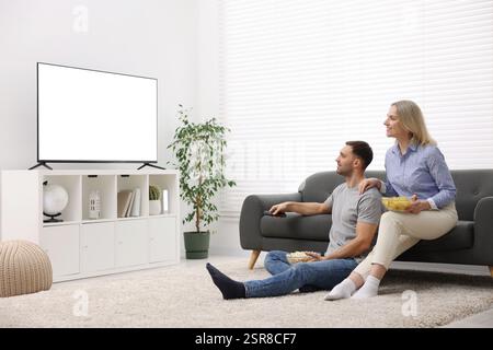 Lovely couple with snacks watching tv at home Stock Photo - Alamy