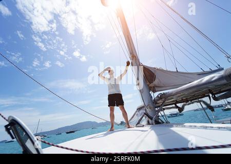 Male captain on deck of sailboat opening sails pulling the rope Stock ...