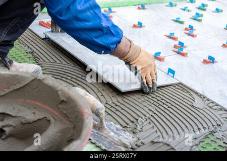 Bricklayer tiler places tiles of a new floor on the glue. Construction ...