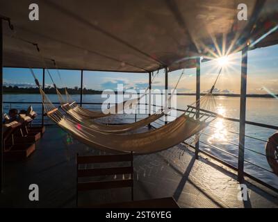 Sunset and hammocks on board a luxury tourist ship sailing the Amazon ...