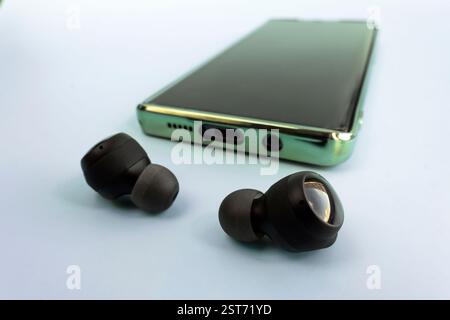 Pair of white wireless earbuds on plain surface. Clean, minimalist ...