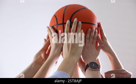 Unity concept. People holding basketball ball together indoors, closeup ...
