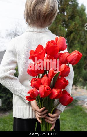 Positive child with tulips, mothers or womens day. Kid hold flowers for ...