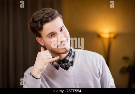 Young man doing call me sign with hand Stock Photo - Alamy