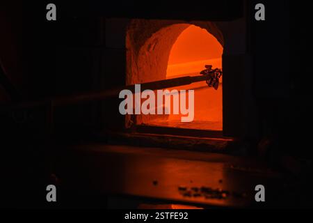 Molten glass on a blowpipe inside of open furnace, glass blowing ...
