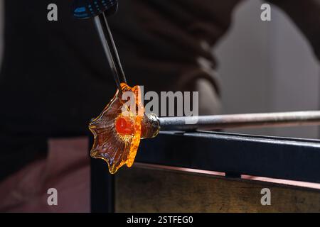 Molding molten glass into a flower shape at glass blowing workshop ...