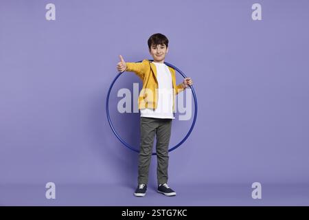 Boy with hula hoop showing thumbs up on yellow background, space for ...