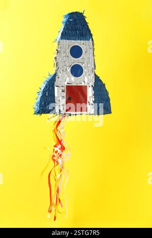 Bright pinata in shape of spaceship, balloons and confetti on table ...