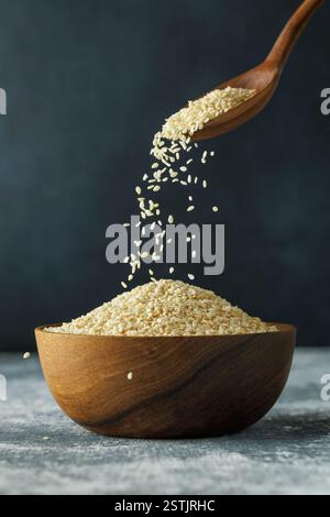 black sesame seeds falling from wooden spoon Stock Photo - Alamy