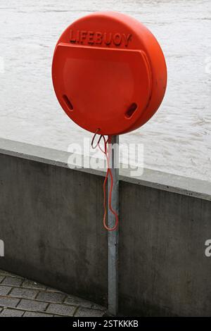 Red lifebuoy in a container on a railing at a body of water Stock Photo ...