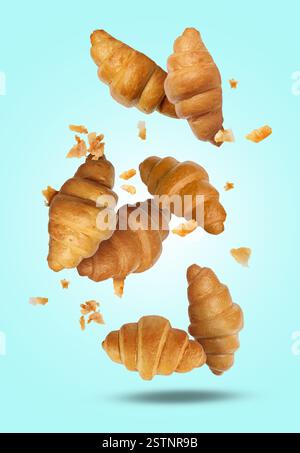 Golden croissants falling on light blue gradient background Stock Photo ...