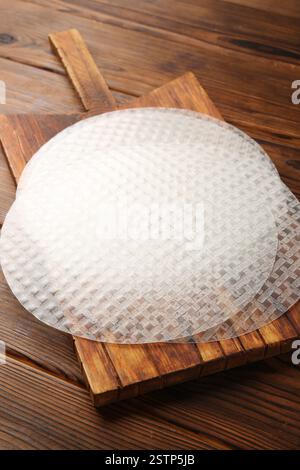 Edible rice paper sheets on dark textured table, top view. Space for ...