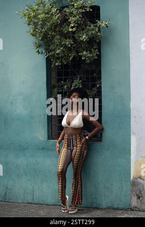 Portrait of happy young African Brazilian woman smiling against yellow ...