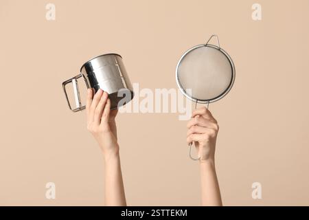Female hands with sieves on beige background Stock Photo - Alamy