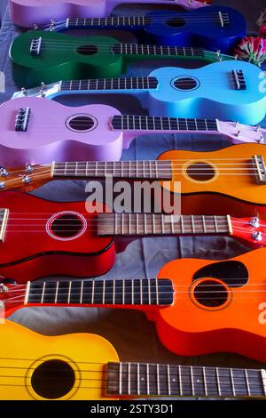 A vibrant row of small ukuleles in various bright colours, neatly lined ...